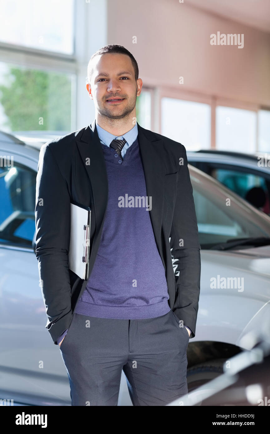 Man standing beside a car in a dealership Stock Photo - Alamy