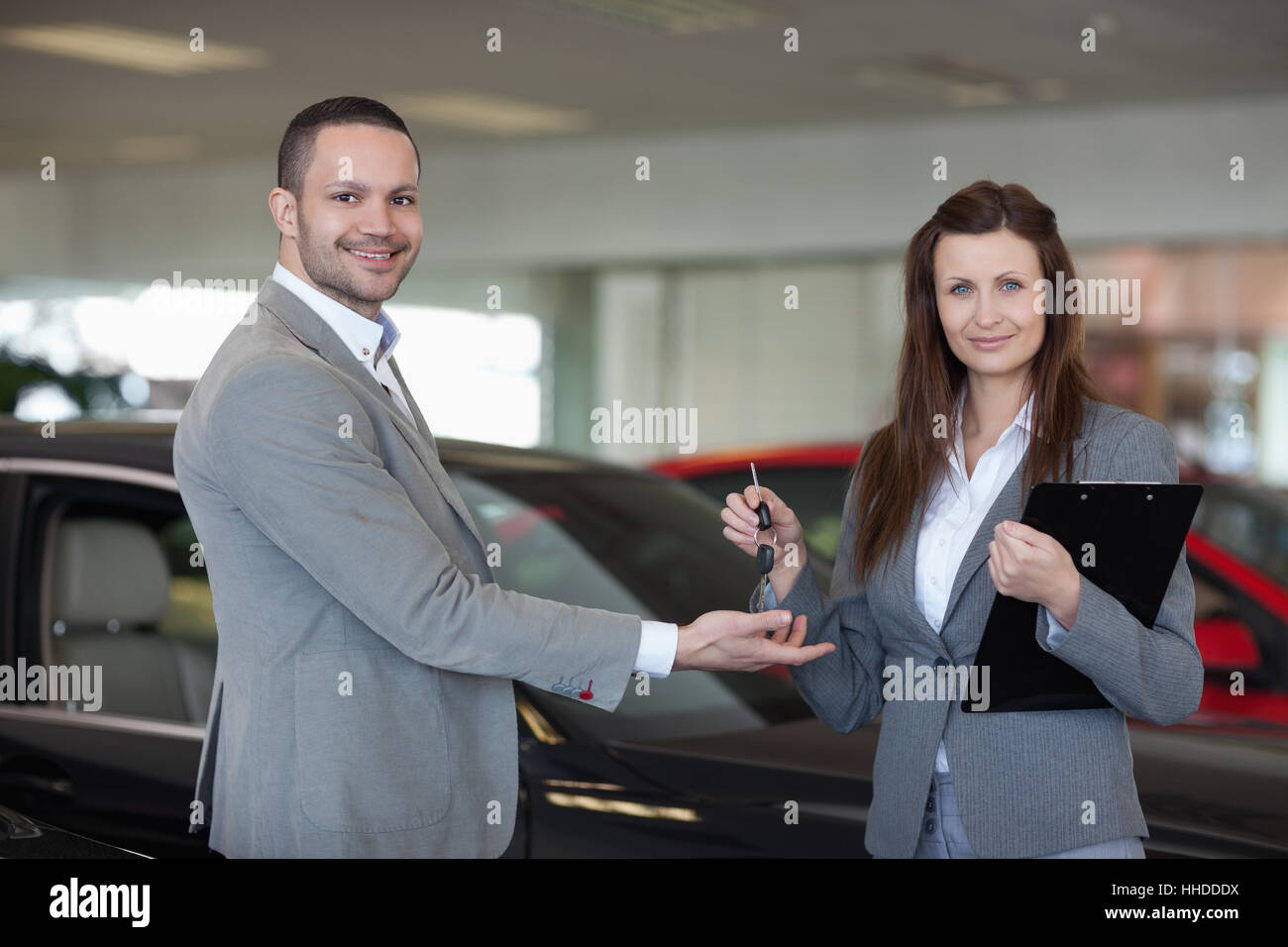 Woman giving car keys to a man in a dealership Stock Photo - Alamy