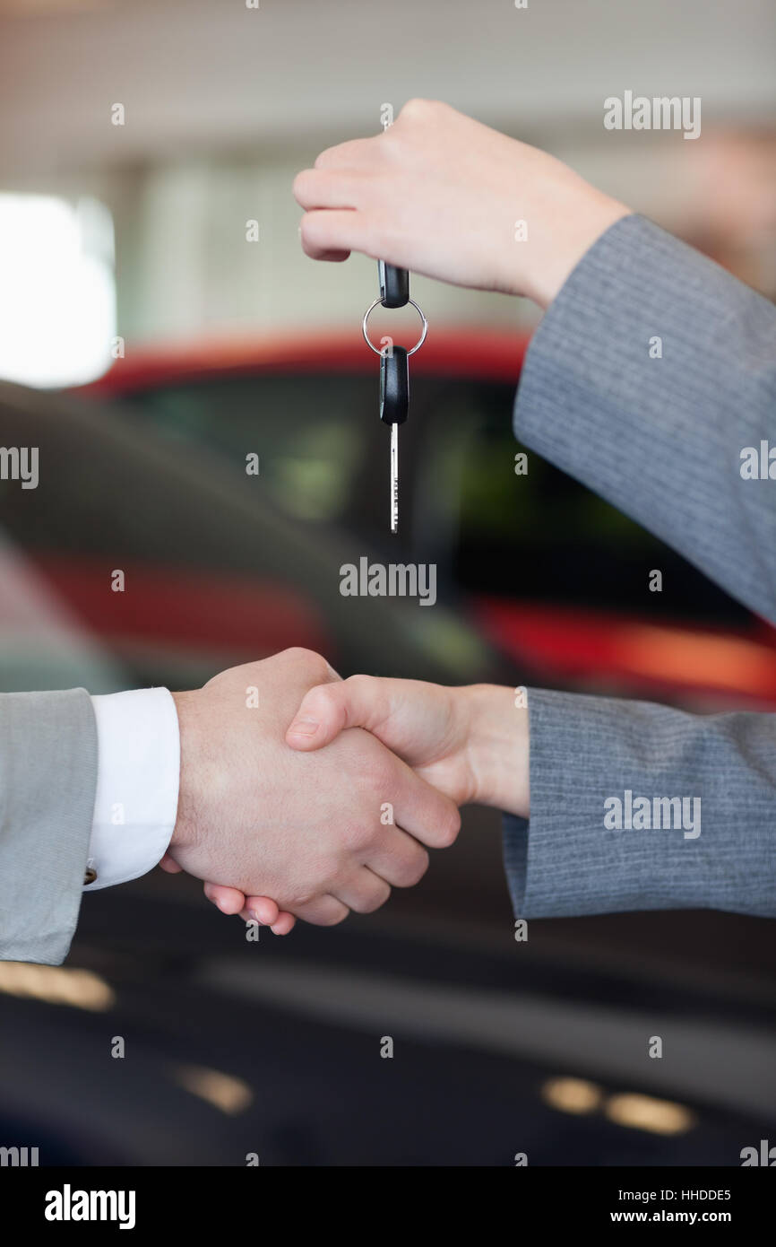 Close up of a woman giving car keys to a man in a dealership Stock ...