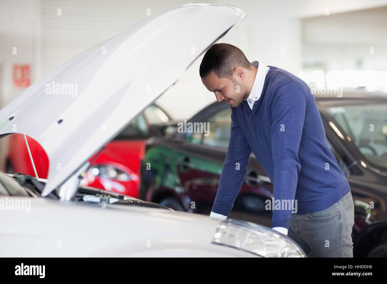 Man thinking about a car engine in a garage Stock Photo - Alamy
