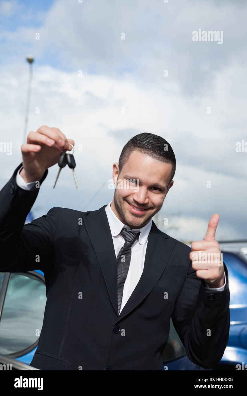 Man holding car keys while raising his thumb outdoors Stock Photo - Alamy