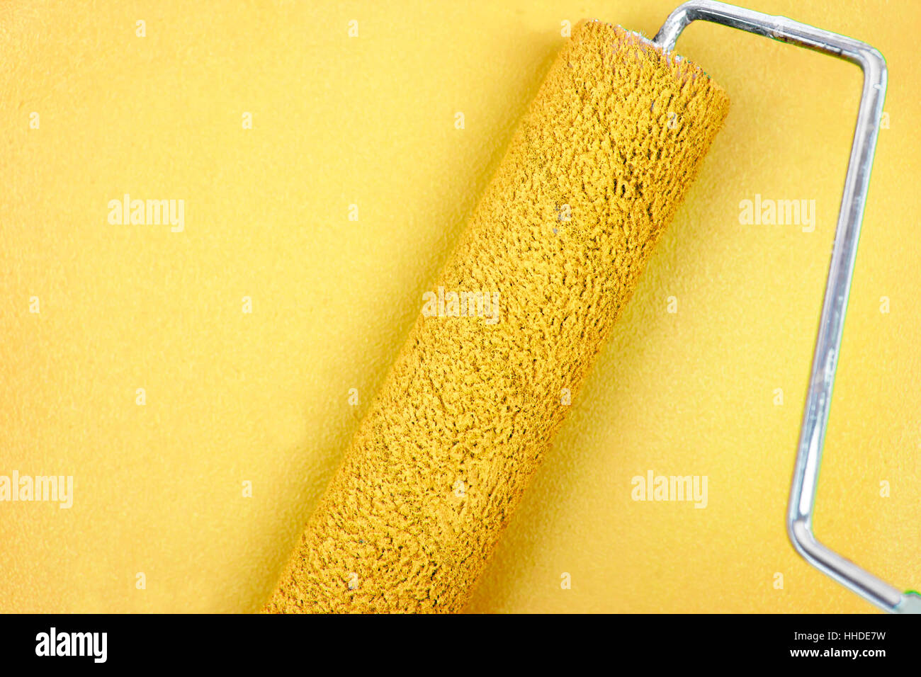 Yellow background with a paint roller in the middle Stock Photo - Alamy