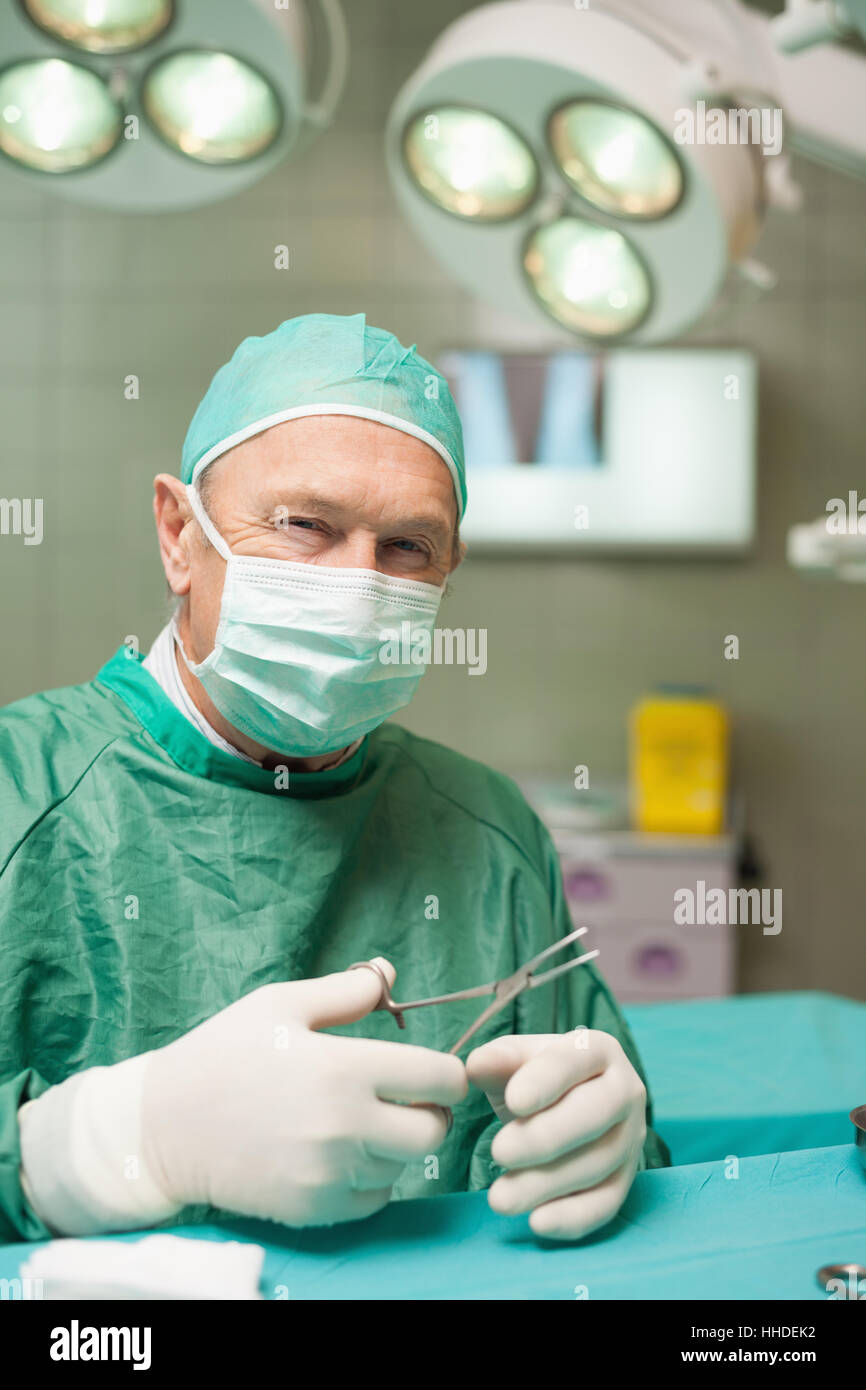 Smiling doctor holding scissors in a surgical room Stock Photo - Alamy