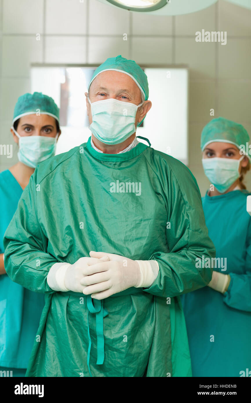 Surgeon joining his hand with interns behind him in a surgical room ...