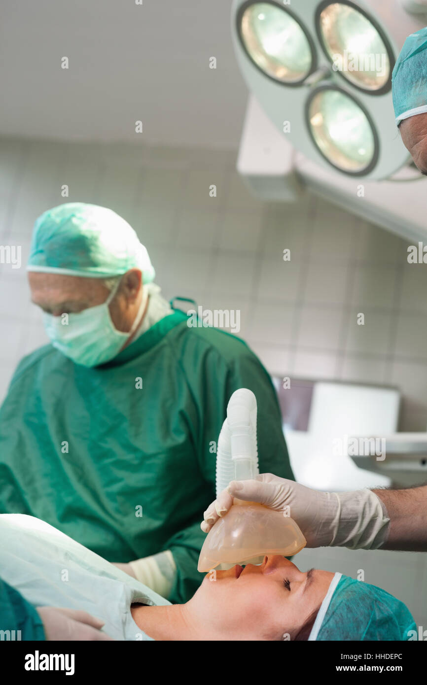 Surgeon placing a mask on the face of a patient in a surgical room ...