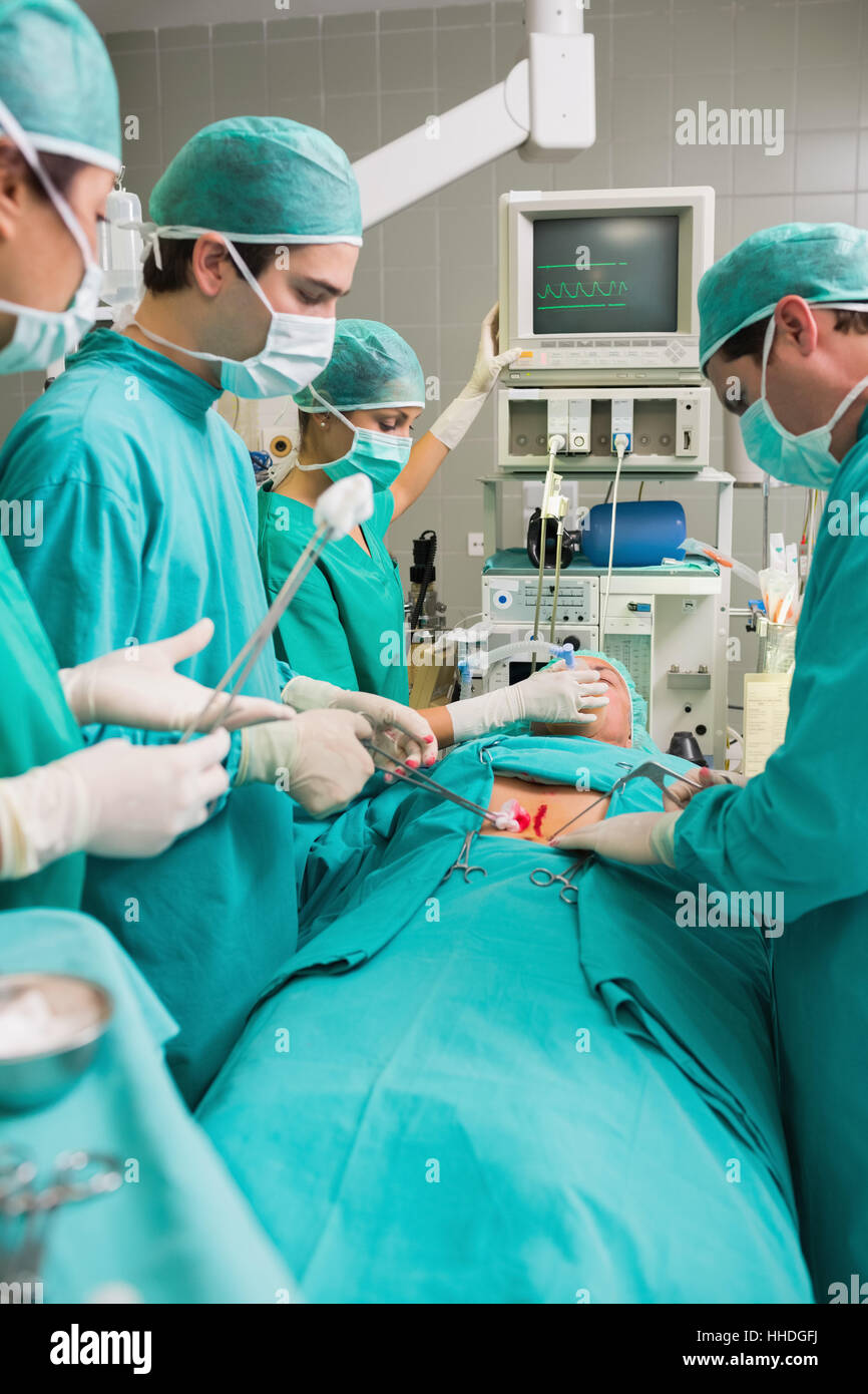 Side view of a surgical team next to a patient in an operating theatre ...