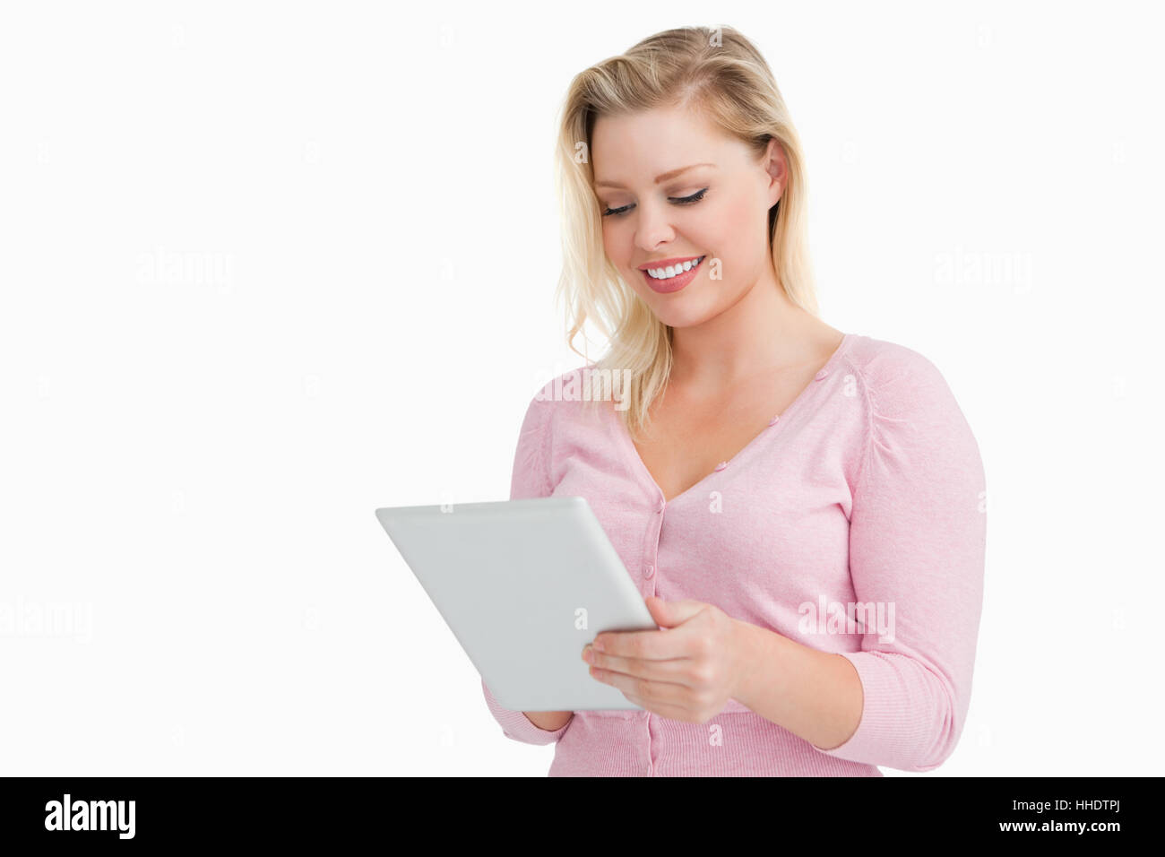 Blonde woman standing while using her touchscreen against a white ...