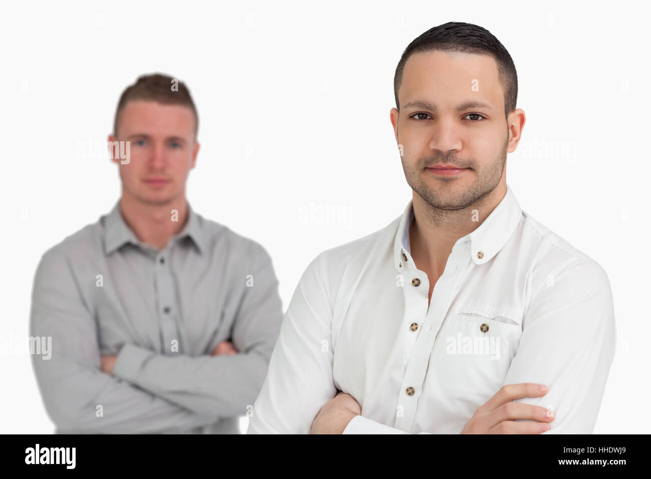 Two men standing while crossing their arms against a white background ...