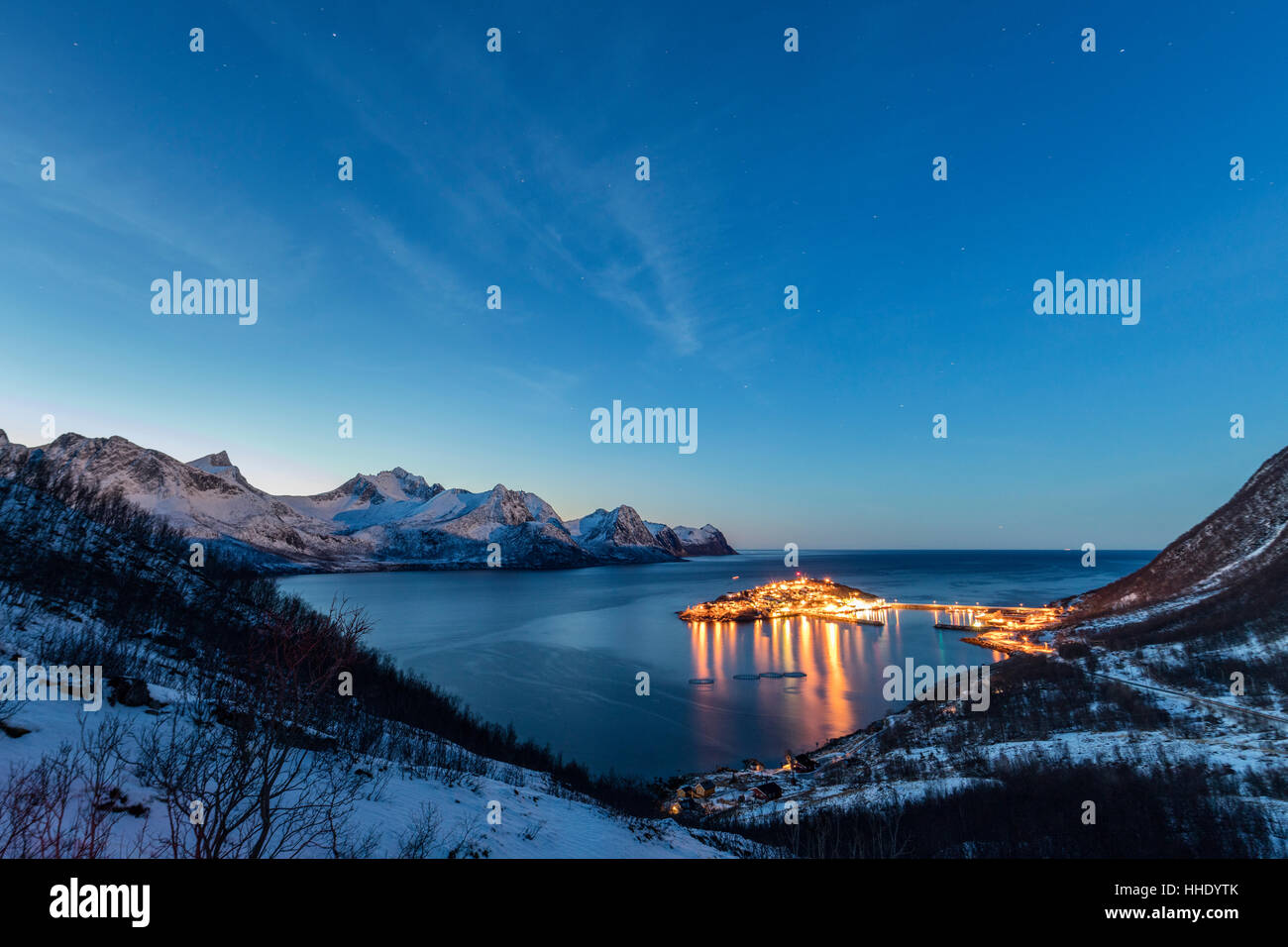 Lights on the typical fishing village framed by the frozen sea at dusk ...