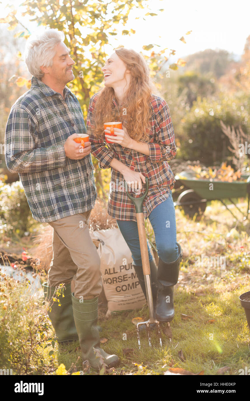Couple laughing enjoying coffee break gardening sunny autumn garden ...