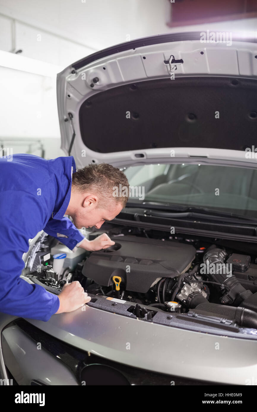 Mechanic looking inside an engine of car in a garage Stock Photo - Alamy