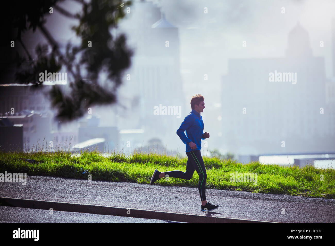 Male runner running on sunny urban sidewalk Stock Photo - Alamy
