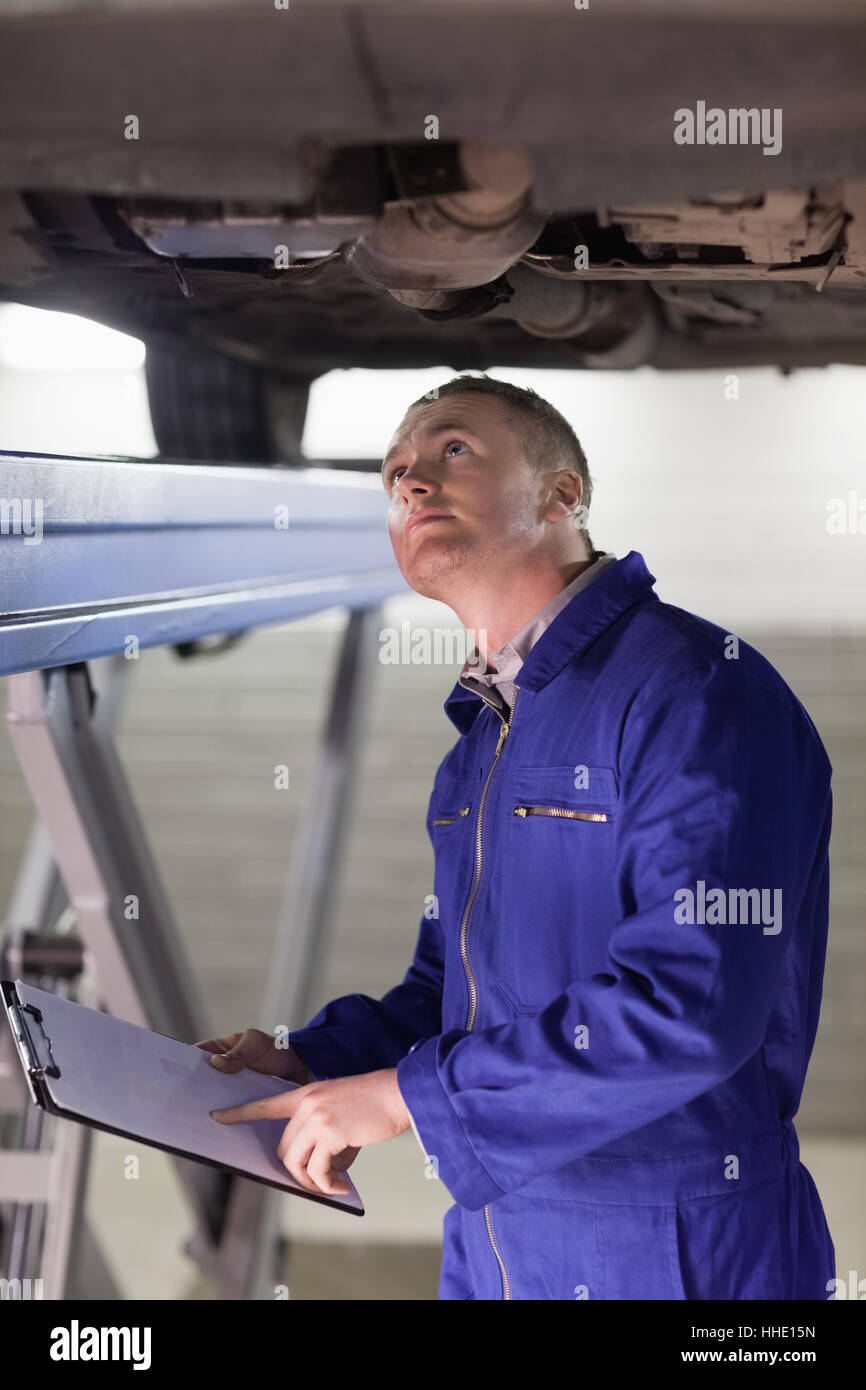 Mechanic looking at the below of a car in a garage Stock Photo - Alamy