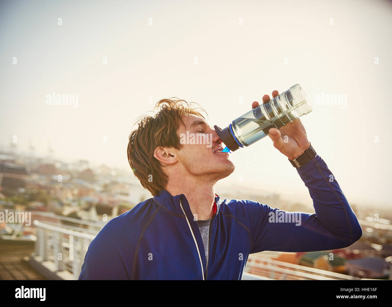 Male runner drinking water on urban footbridge Stock Photo - Alamy
