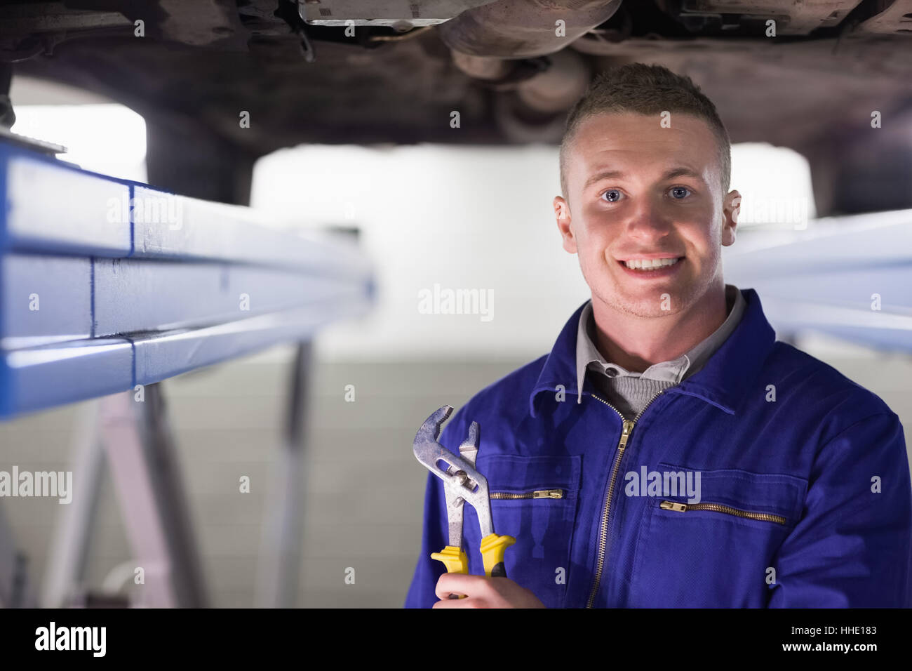 Smiling mechanic holding an adjustable pliers in a garage Stock Photo ...