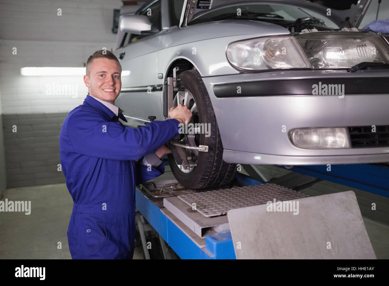 Smiling mechanic standing while repairing a car wheel in a garage Stock ...
