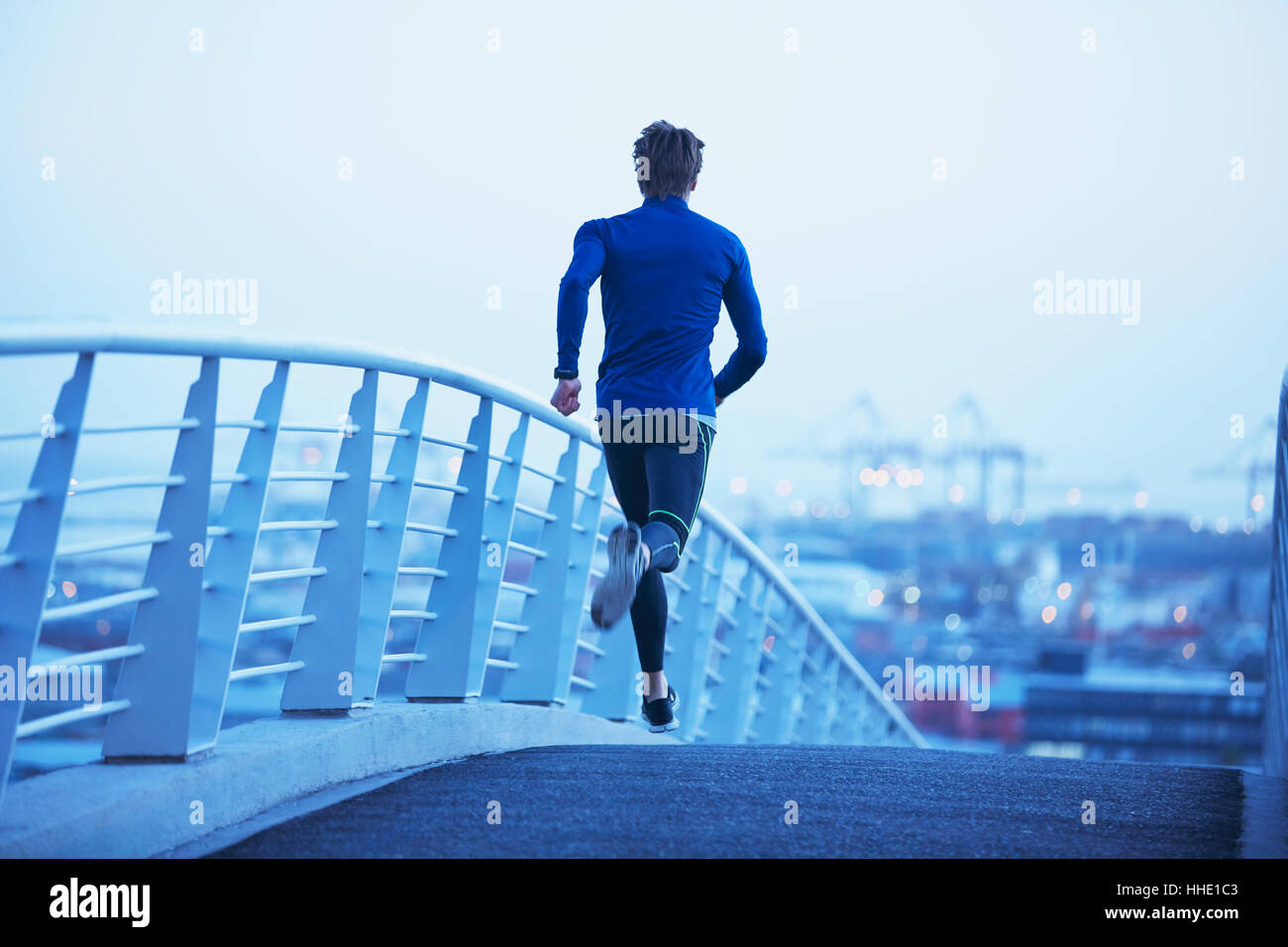 Male runner running on urban footbridge at dawn Stock Photo - Alamy