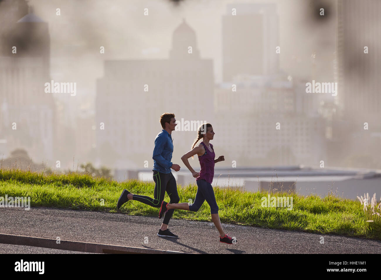 Runner couple running on sunny urban city sidewalk Stock Photo - Alamy