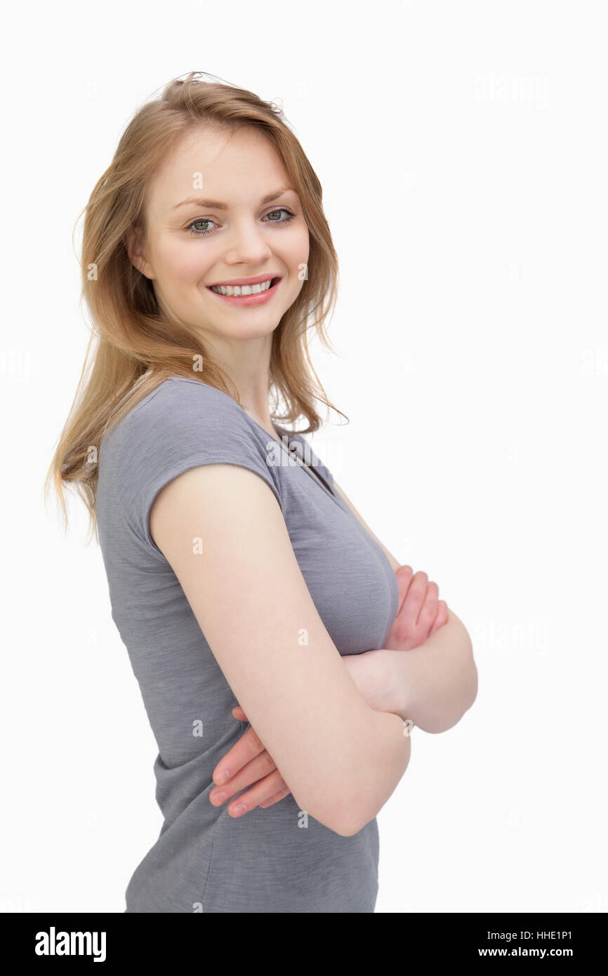 Side view of a woman smiling while looking at camera against a white ...