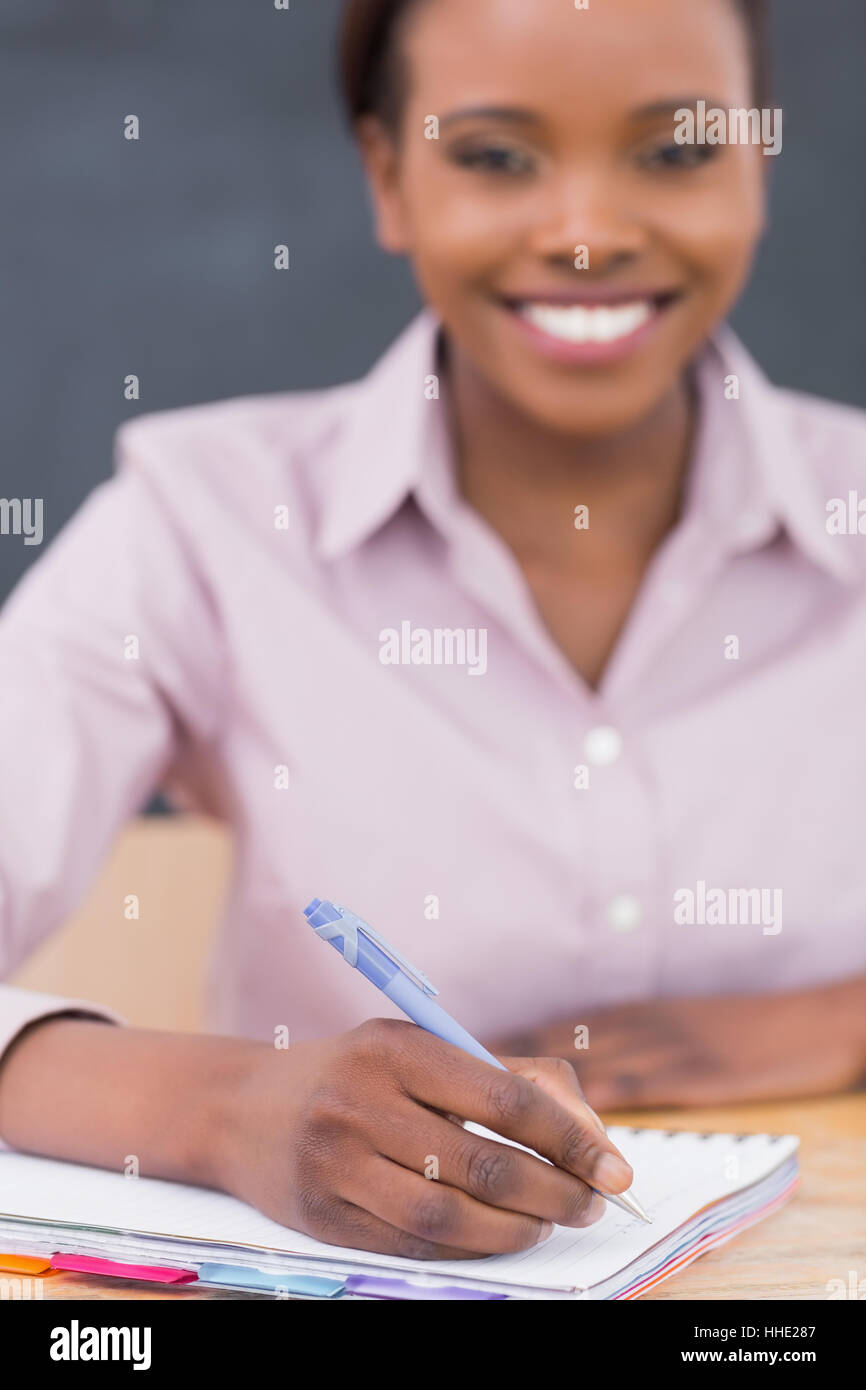 Focus on a teacher writing on a notebook in a classroom Stock Photo - Alamy