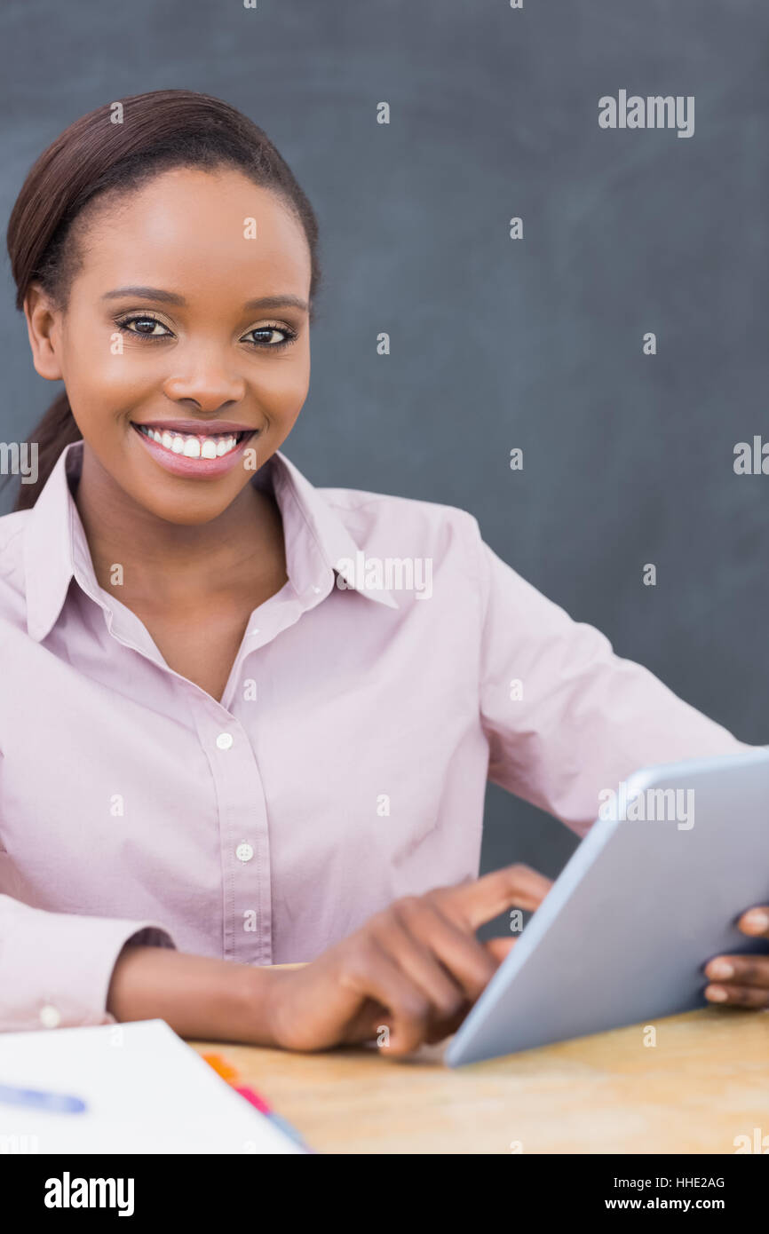 Teacher looking at camera while using a tablet computer in a classroom ...