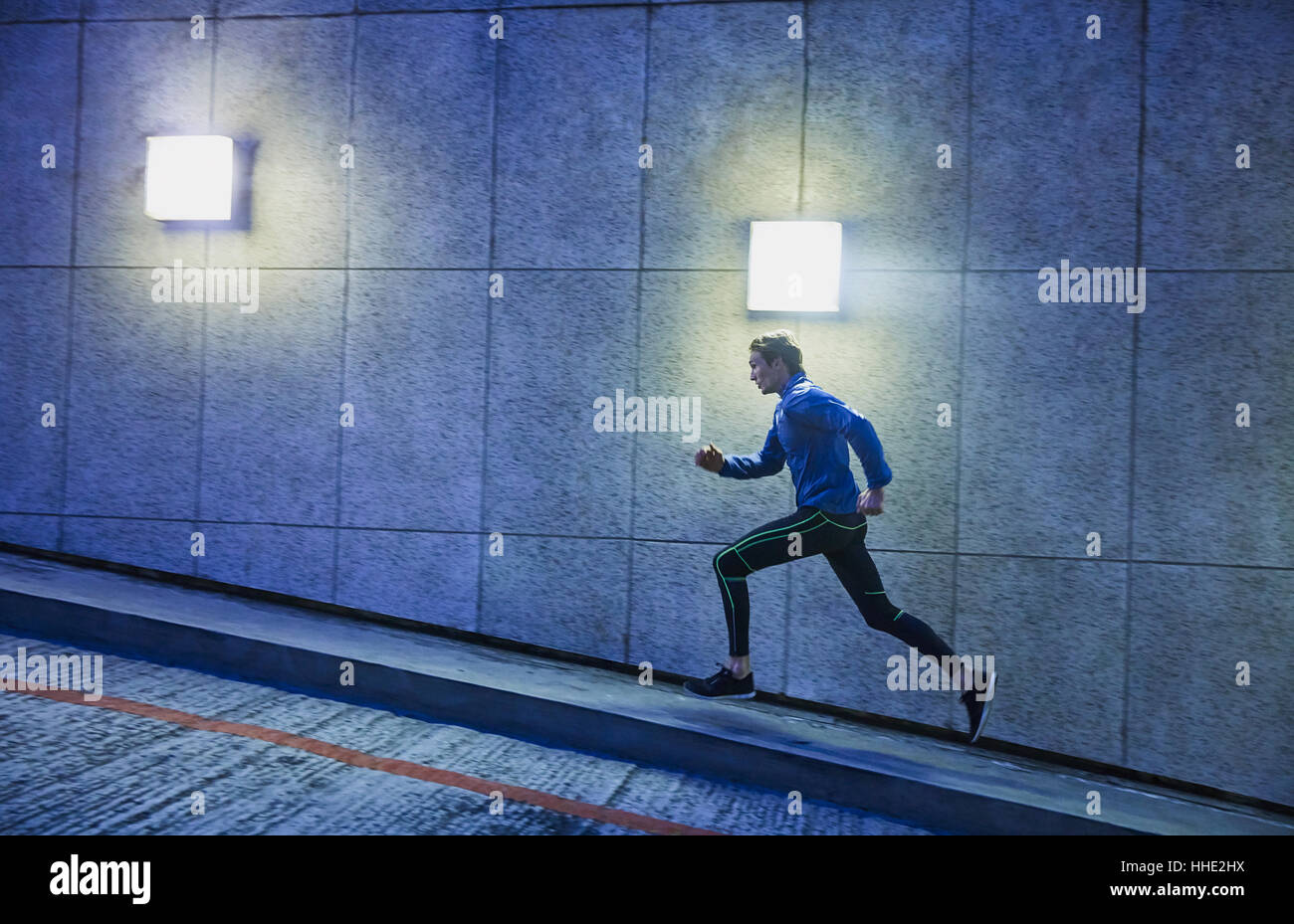 Male runner running ascending illuminated urban ramp Stock Photo - Alamy