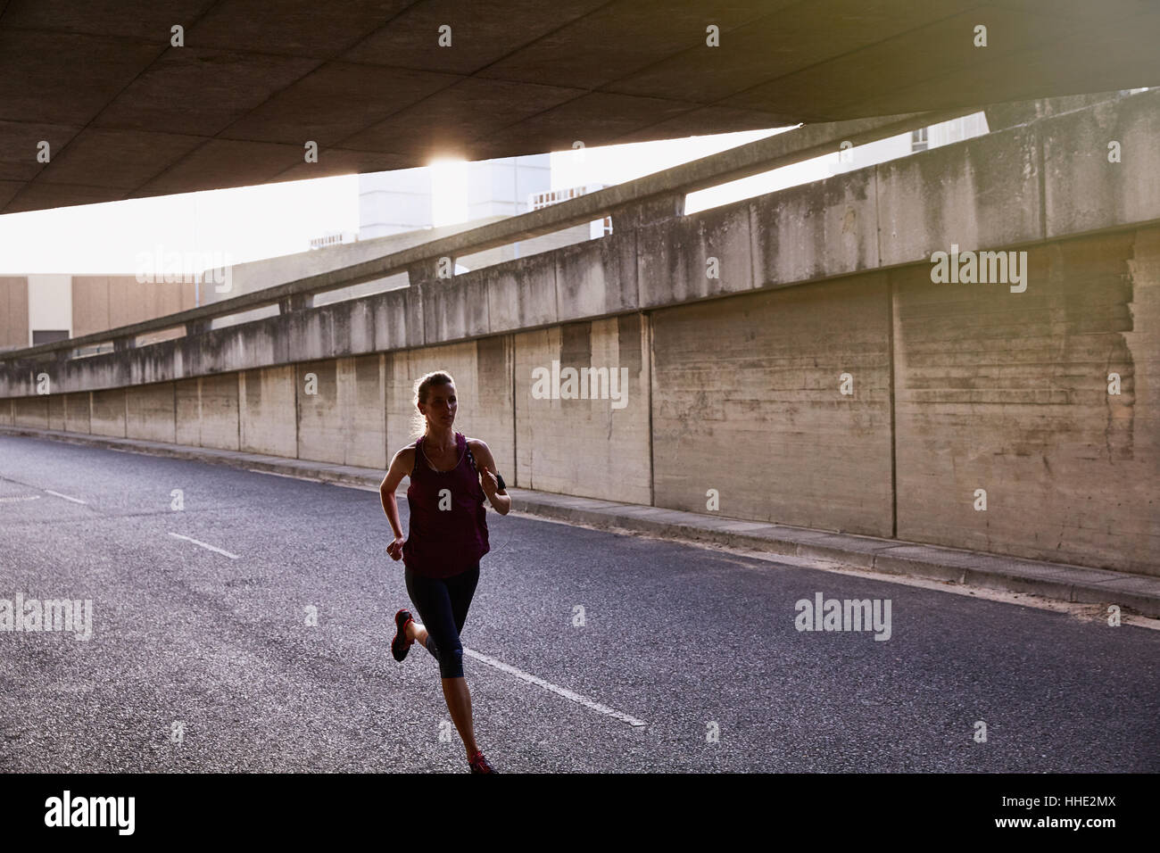 Female runner running into urban tunnel Stock Photo - Alamy