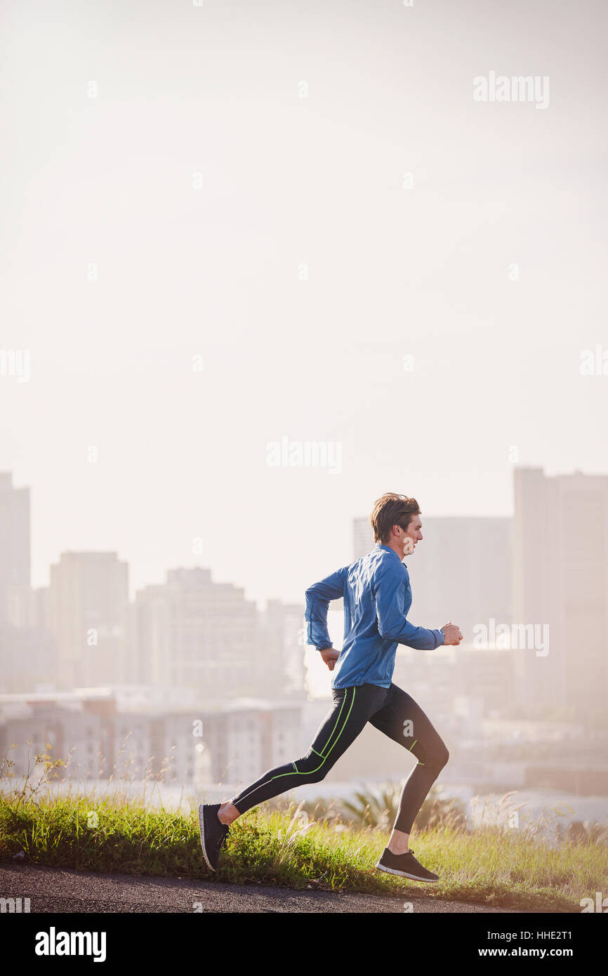 Male runner running on sunny urban city street Stock Photo - Alamy