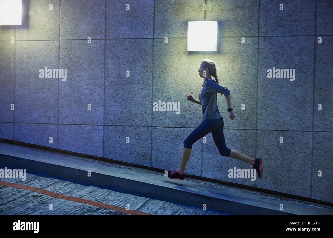 Female runner running ascending illuminated urban ramp Stock Photo - Alamy