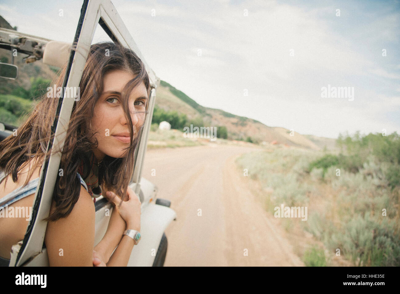 A woman leaning out of a moving jeep on a mountain road Stock Photo - Alamy
