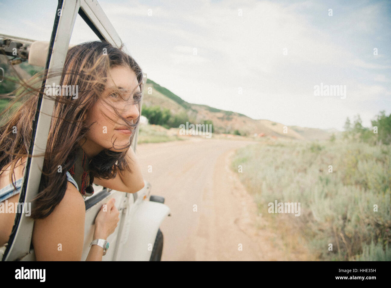 A woman leaning out of a moving jeep on a mountain road Stock Photo - Alamy