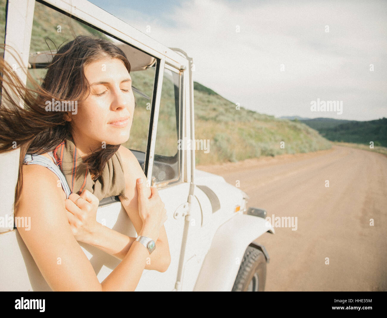 A woman leaning out of a moving jeep on a mountain road Stock Photo - Alamy
