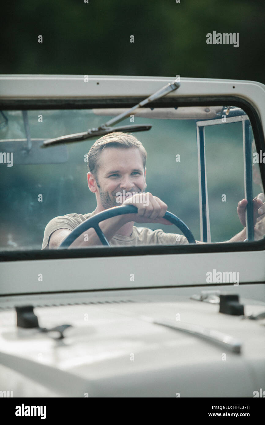 A man at the driving wheel of an open top jeep Stock Photo - Alamy