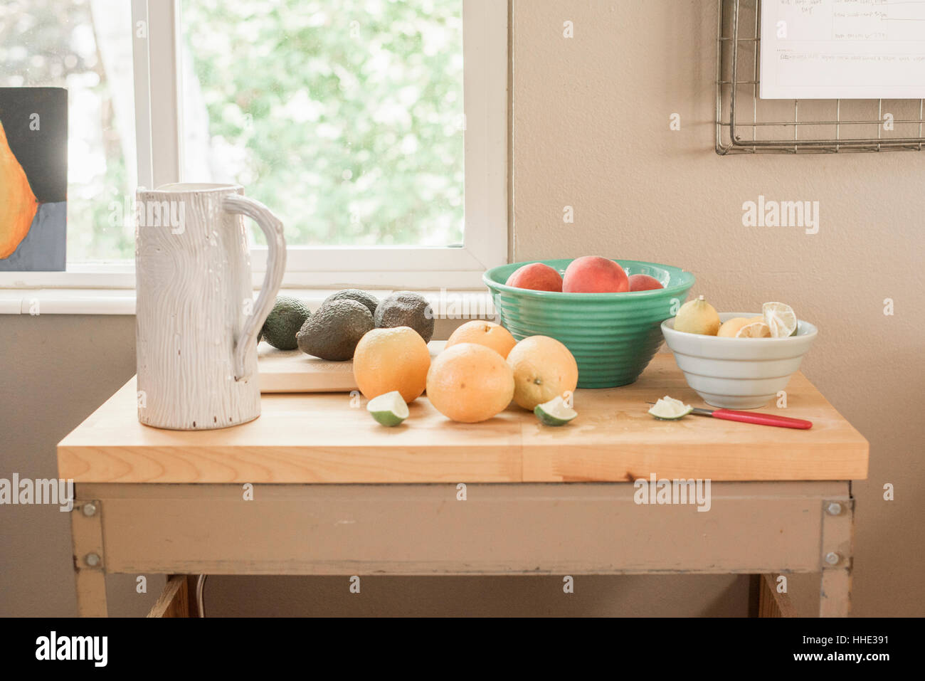 A kitchen table by a window, fresh fruit and avocados in bowls Stock ...