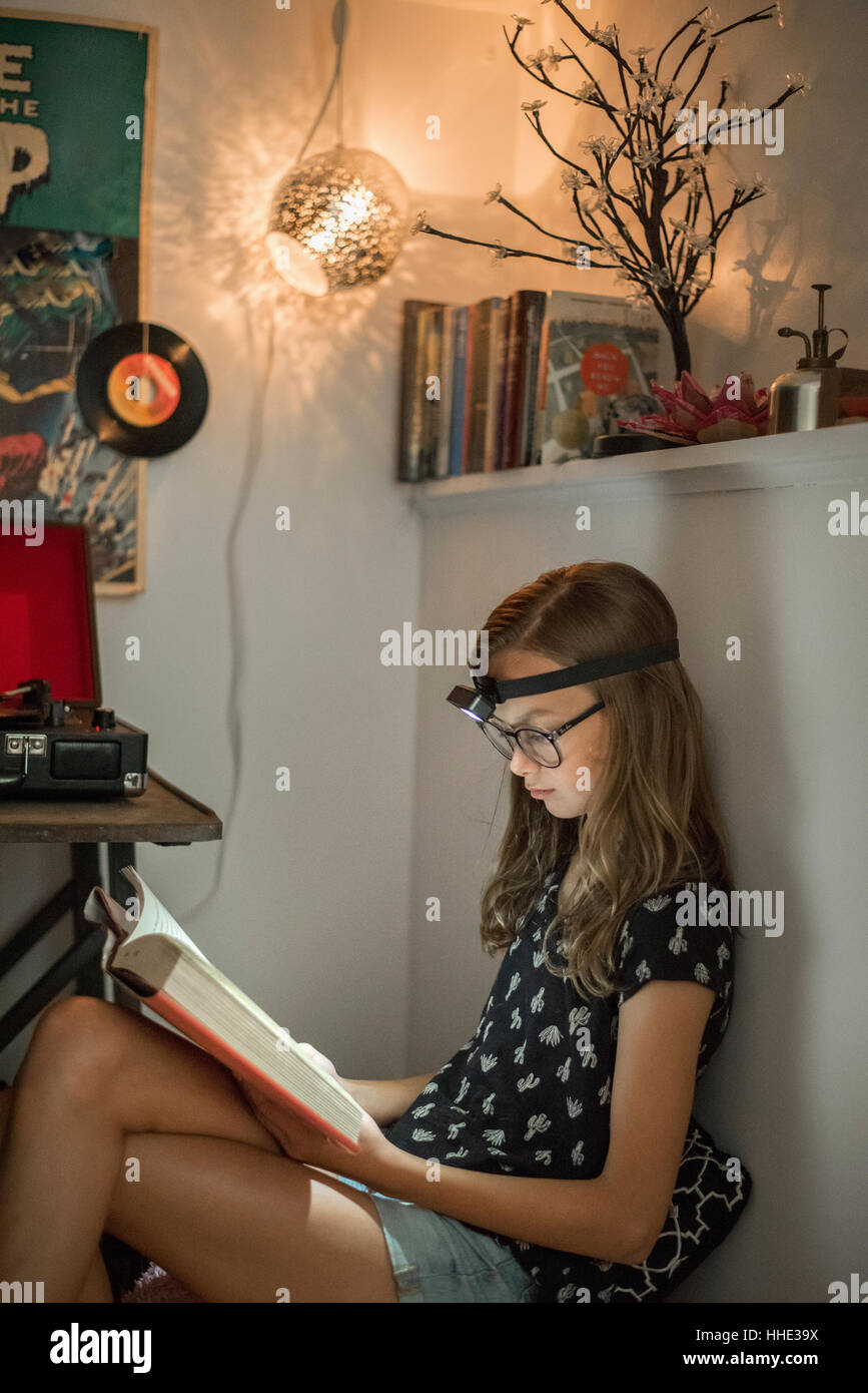 A girl reading a book in a quiet corner using a head torch Stock Photo ...