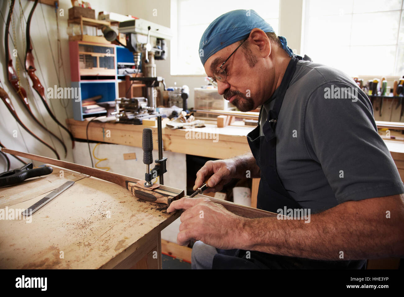 A bow maker working on a wooden bow in his workshop Stock Photo - Alamy