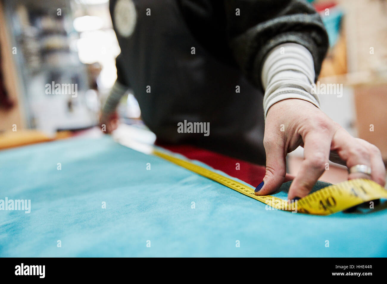 A woman preparing and measuring upholstery fabric on a workbench Stock ...
