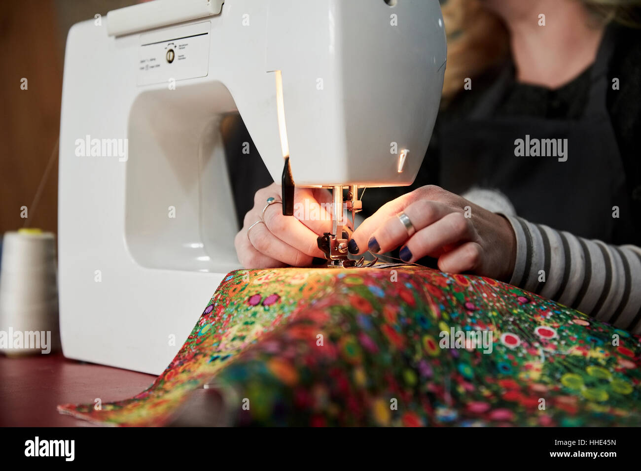 A woman threading a needle on a sewing machine, sewing upholstery ...
