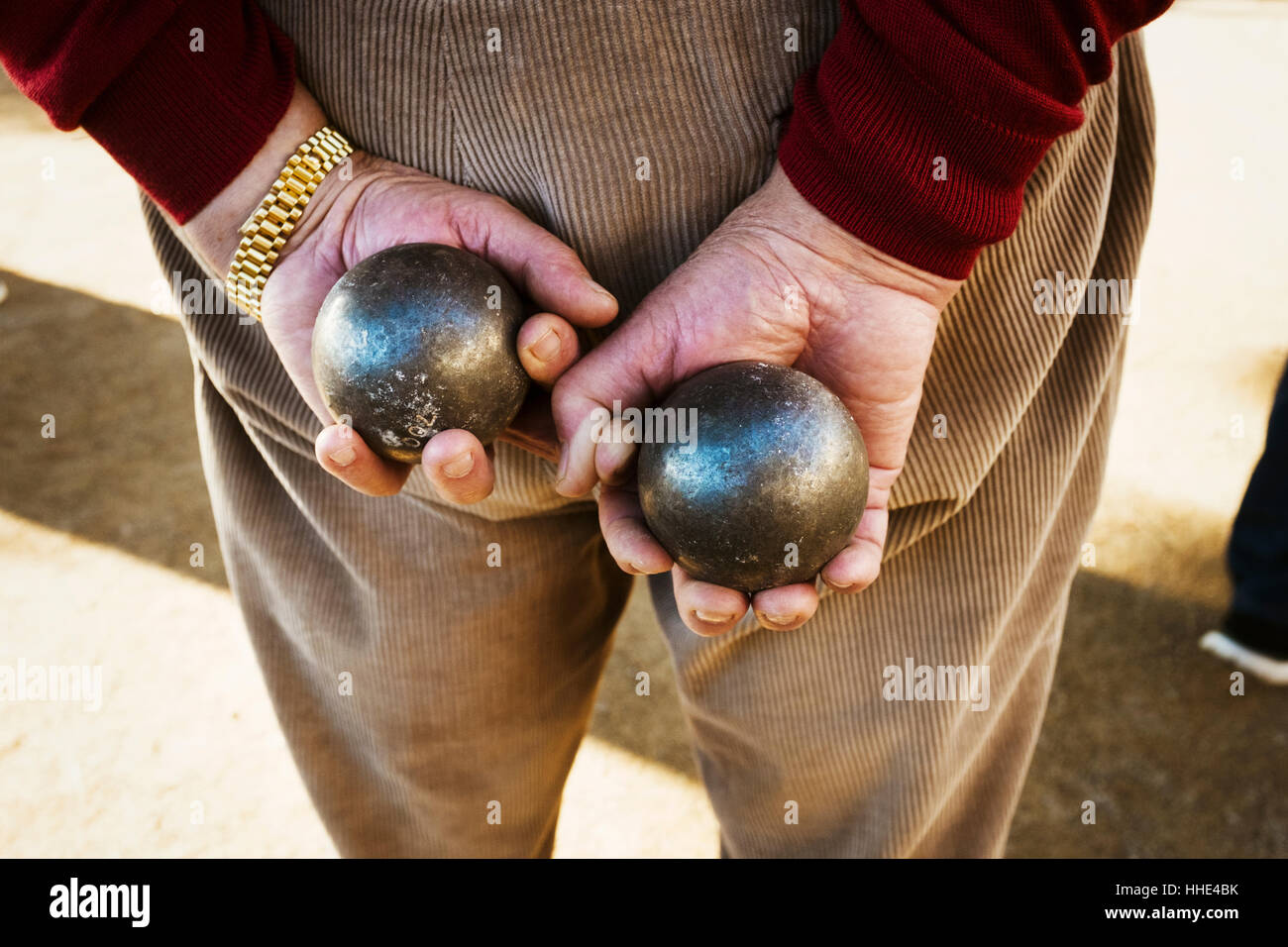A man holding two boules, small metals balls in his hands behind his ...