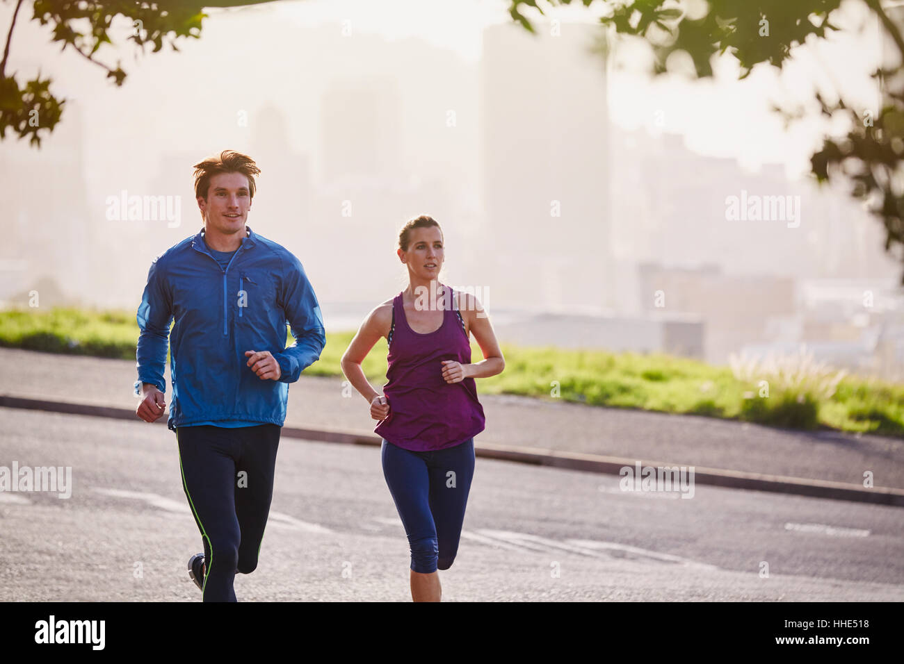 Runner couple running on sunny urban city street Stock Photo - Alamy