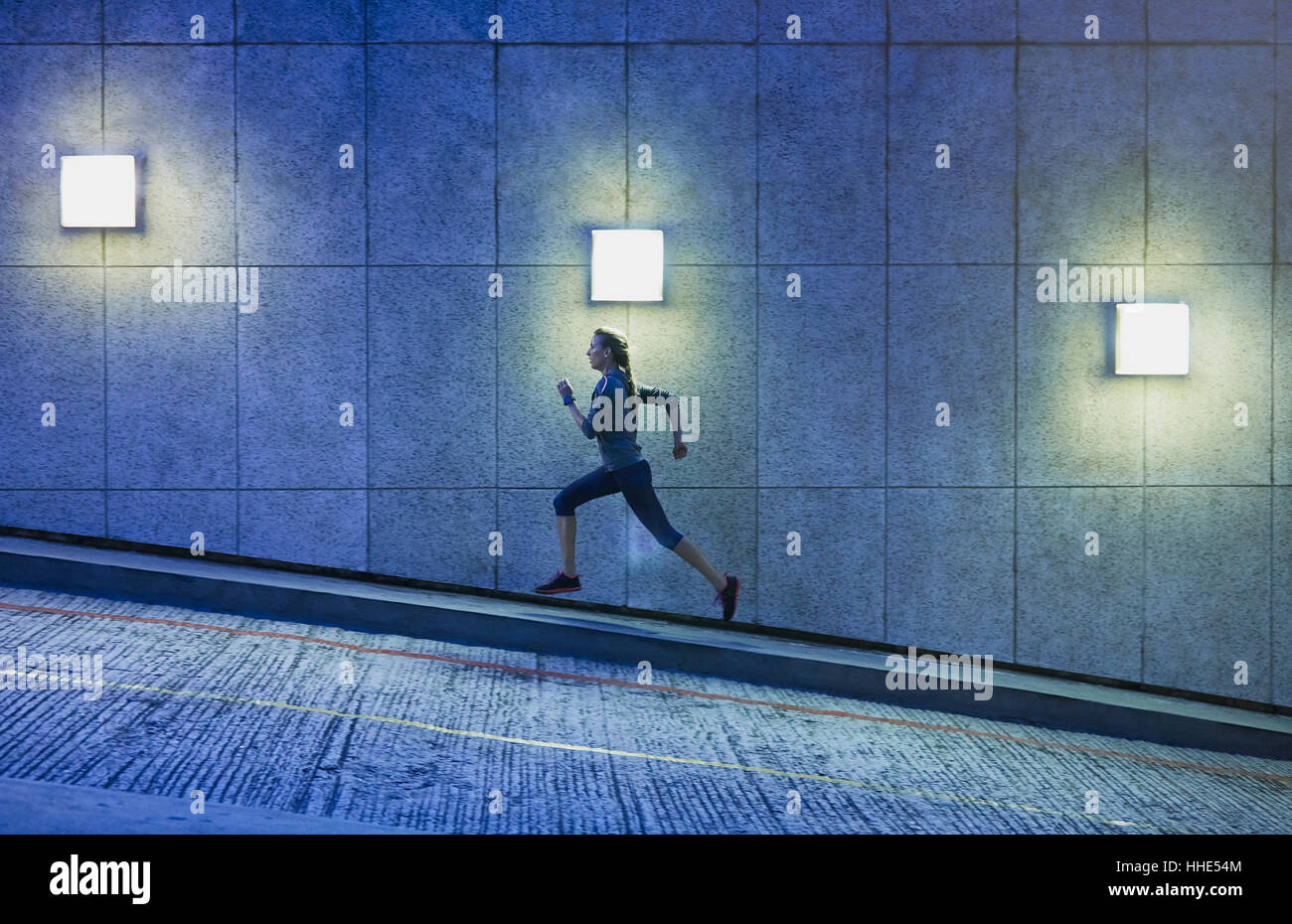 Female runner running ascending illuminated urban ramp Stock Photo - Alamy