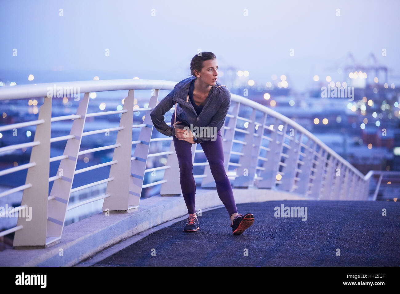 Female runner stretching leg on urban footbridge Stock Photo - Alamy