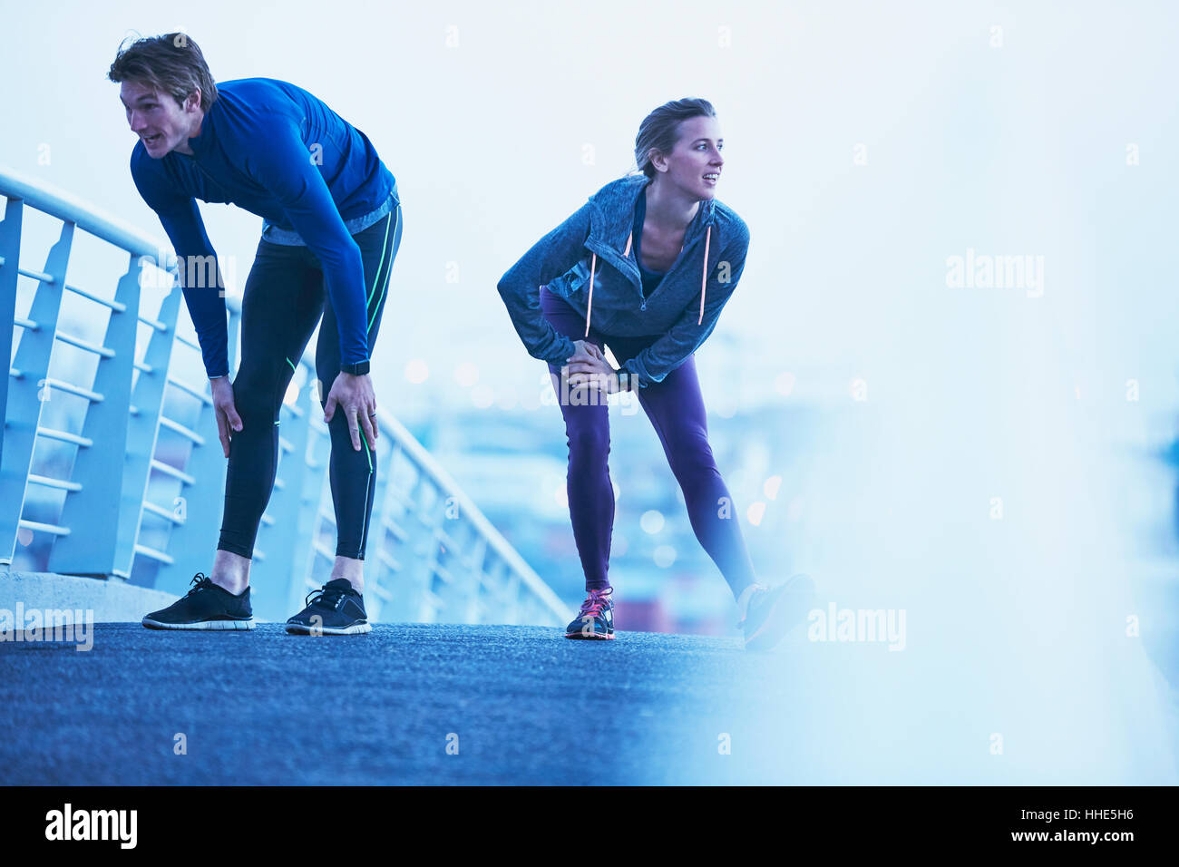 Runner couple stretching legs on footbridge Stock Photo - Alamy