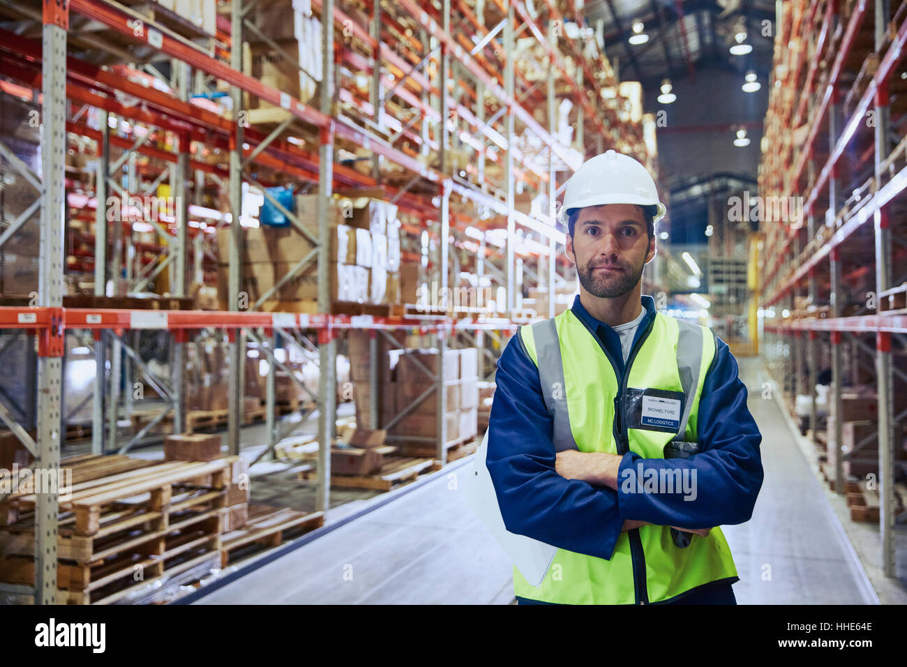 Portrait confident worker with arms crossed in distribution warehouse ...