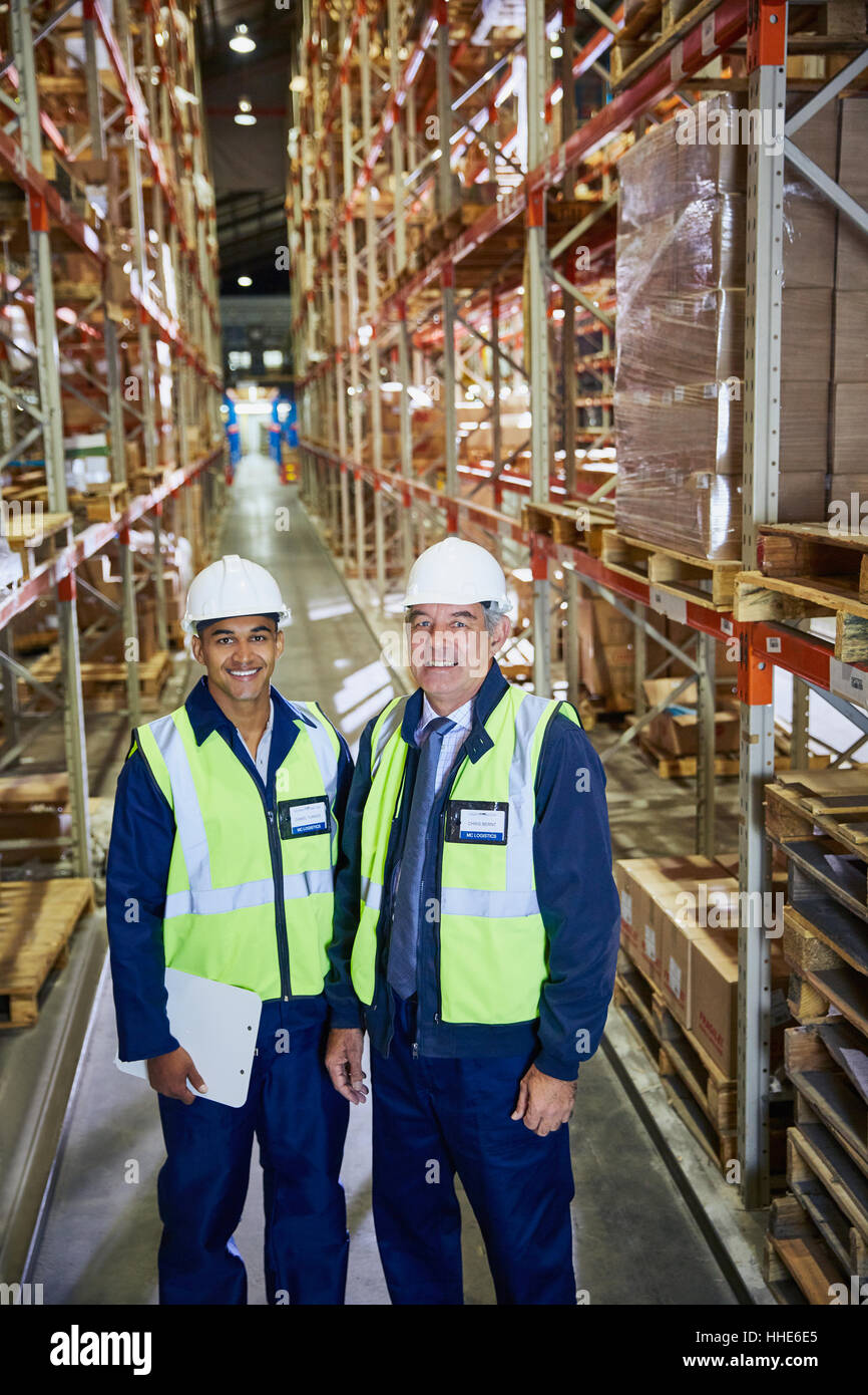Portrait confident manager and worker in distribution warehouse aisle ...