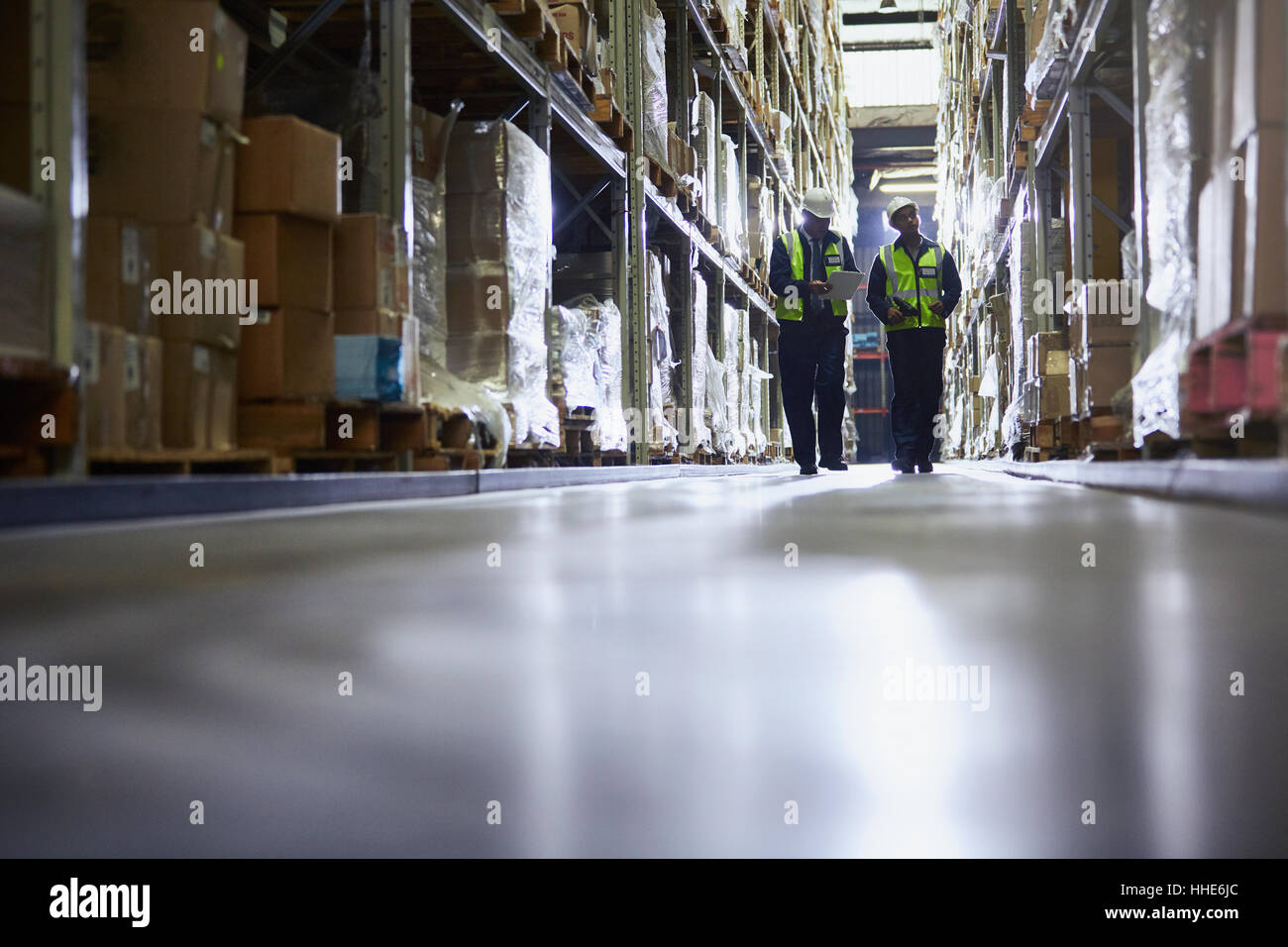 Workers walking in distribution warehouse aisle Stock Photo - Alamy