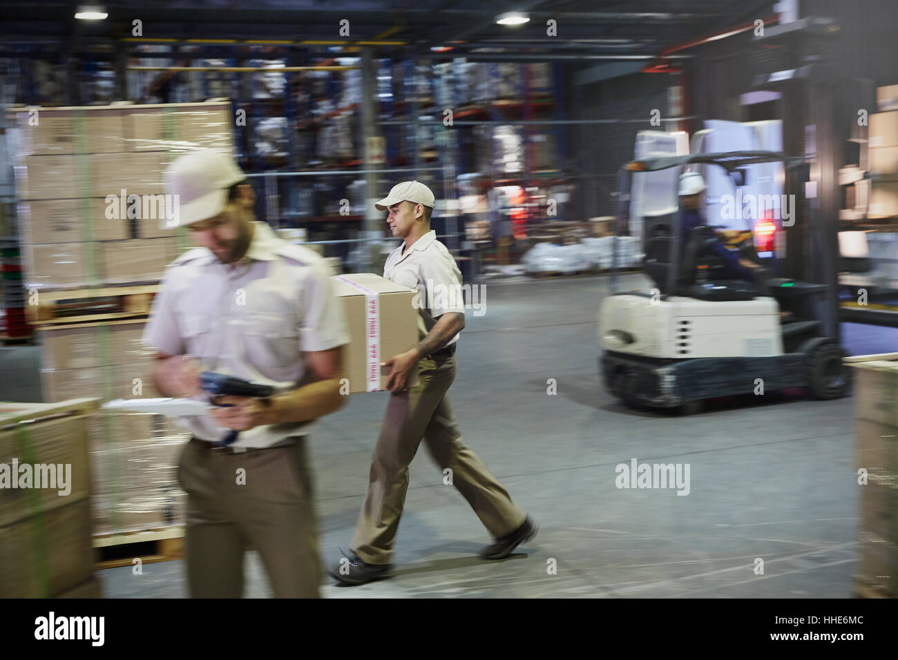 Workers carrying and moving boxes with forklift at distribution ...