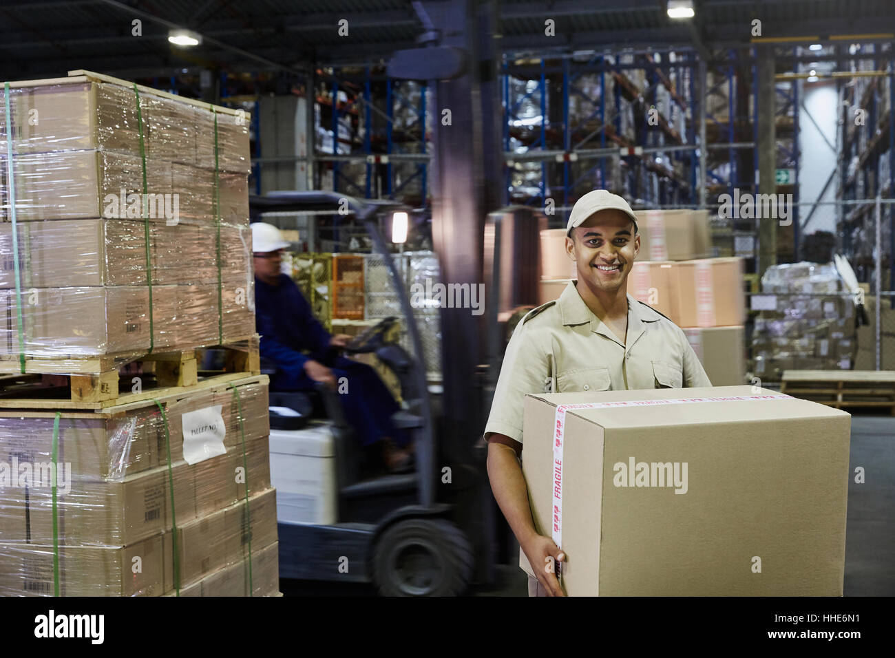 Portrait smiling worker carrying cardboard box at distribution ...