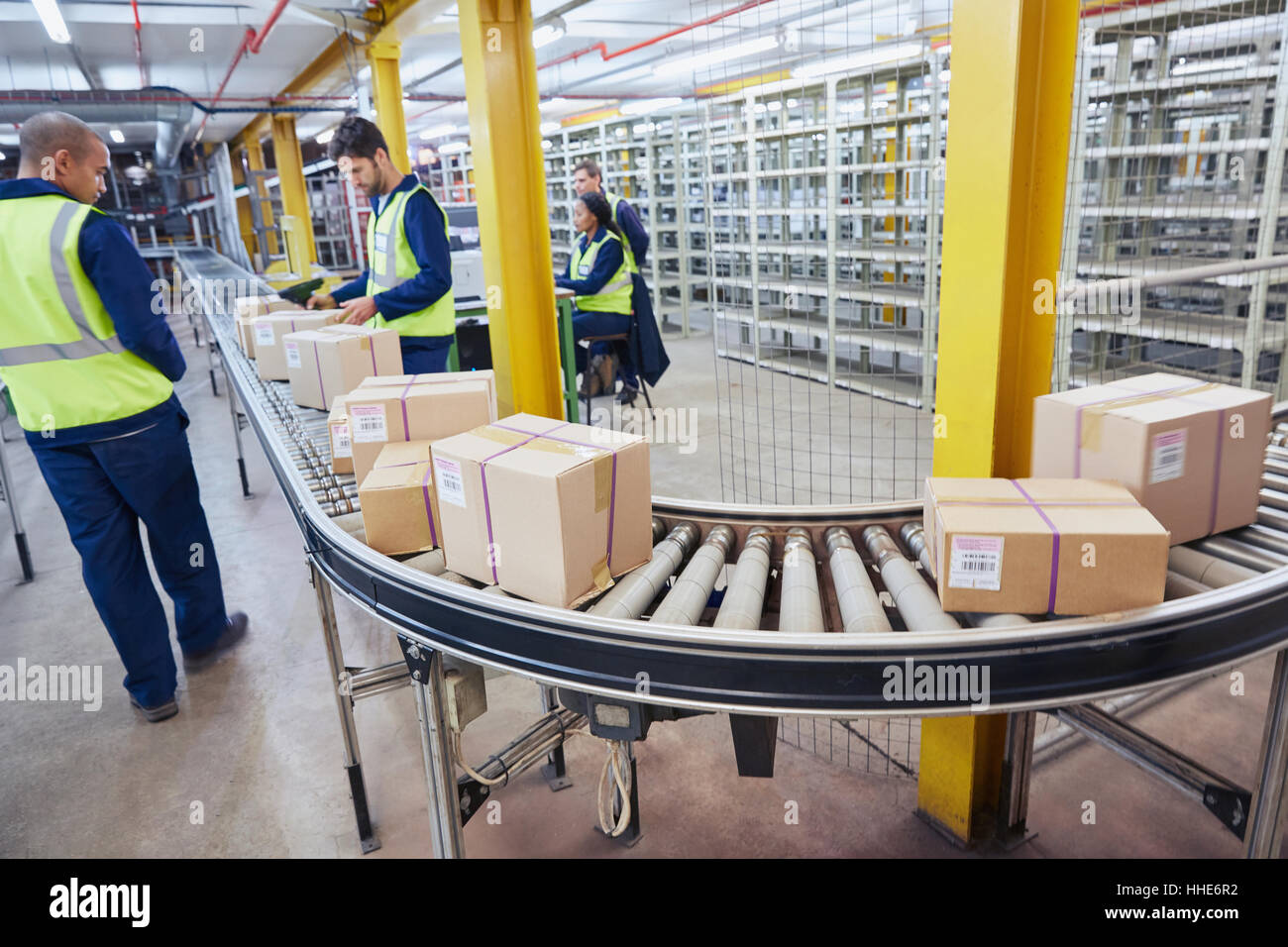 Workers processing cardboard boxes on conveyor belt in distribution ...