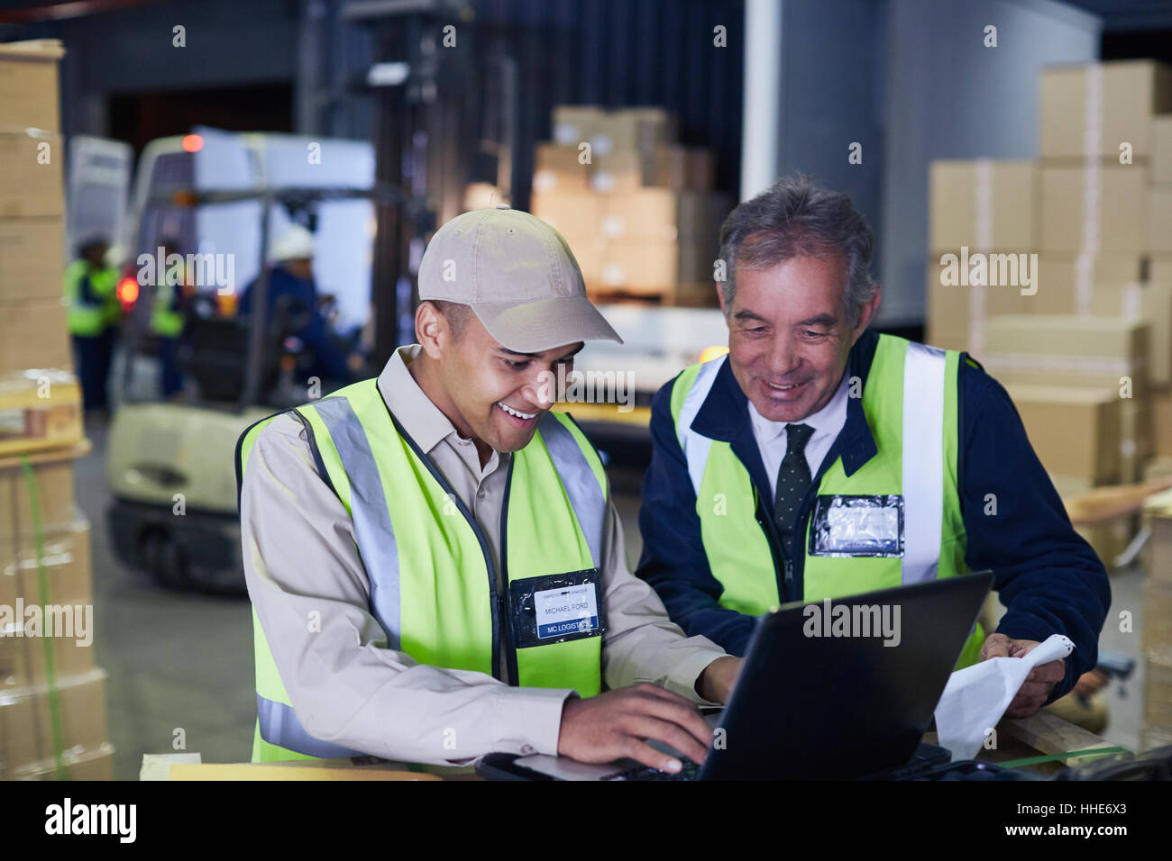 Manager and worker using laptop at distribution warehouse loading dock ...